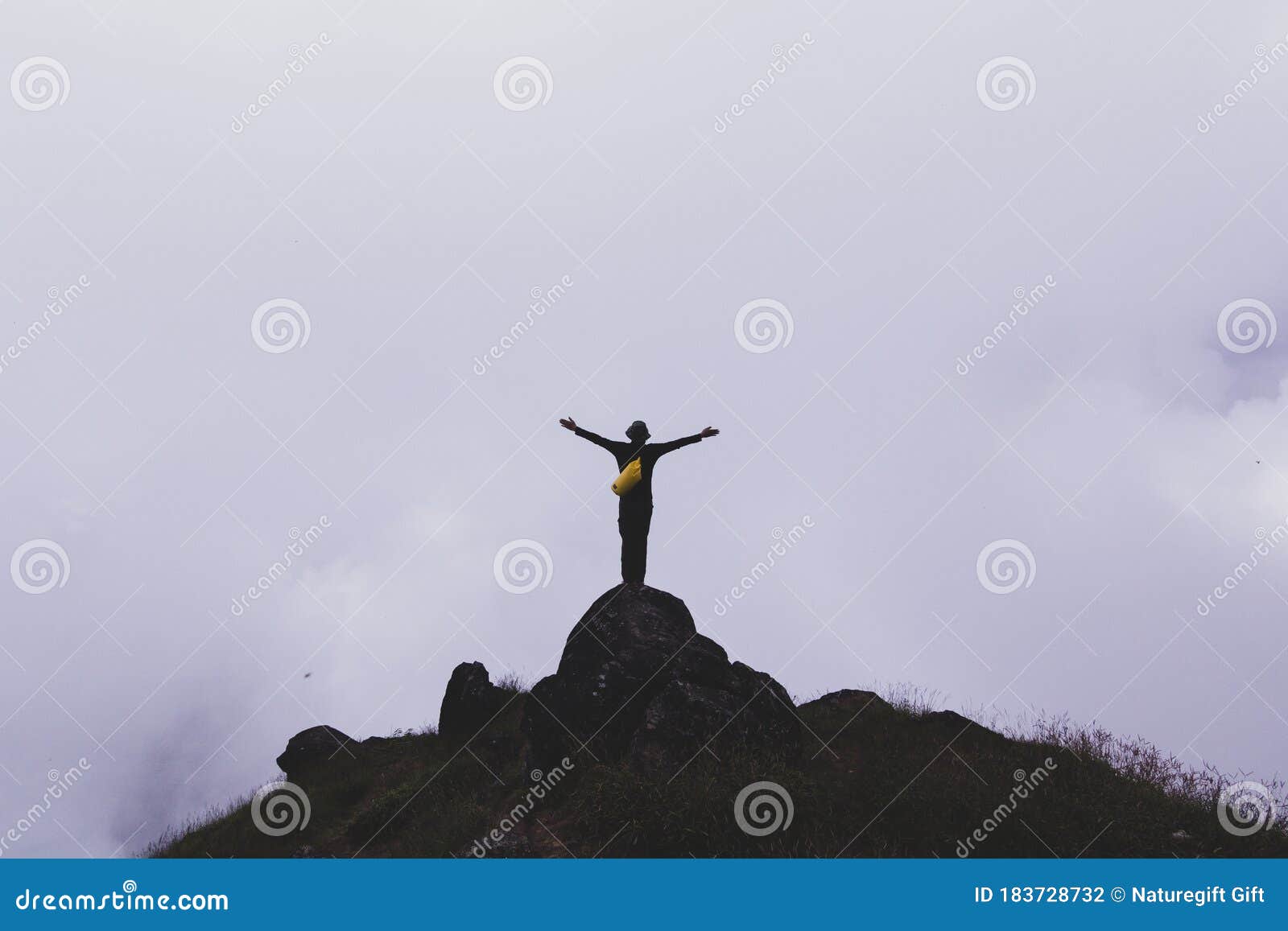 Silhouette Image of Man Standing with Arms Stretched on a Rock with ...