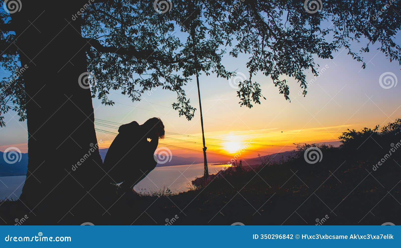 Silhouette of a Man Crouching Under a Tree during a Dramatic Sunset ...