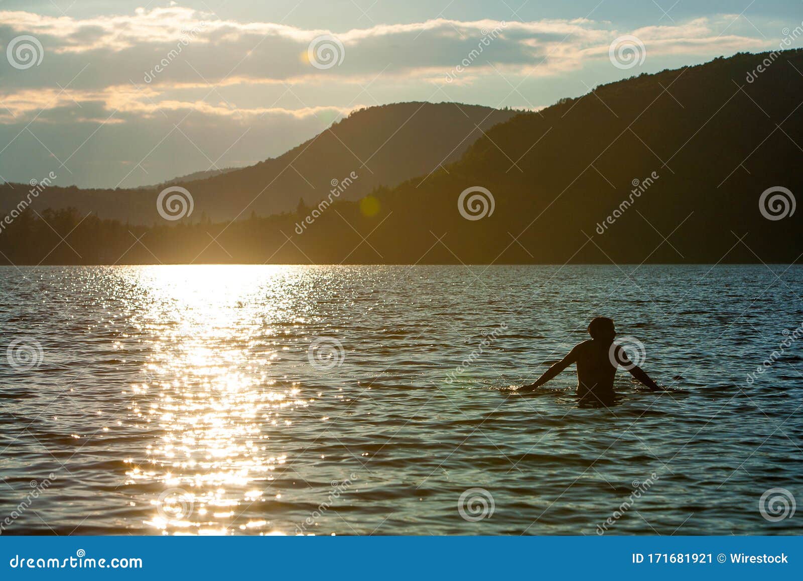 Silhouette of a Man in an Ocean during Sunset with Mountains in the ...