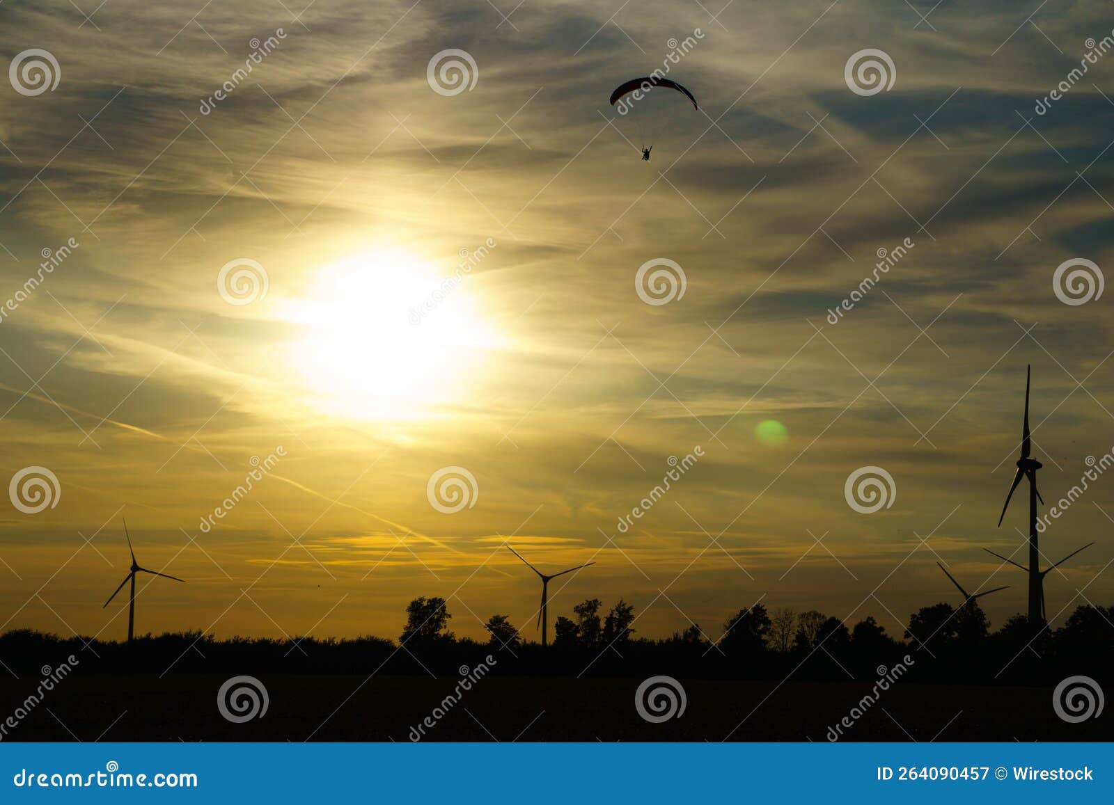 Silhouette of a Paraglider and Wind Turbines Against the Sunset Sky ...