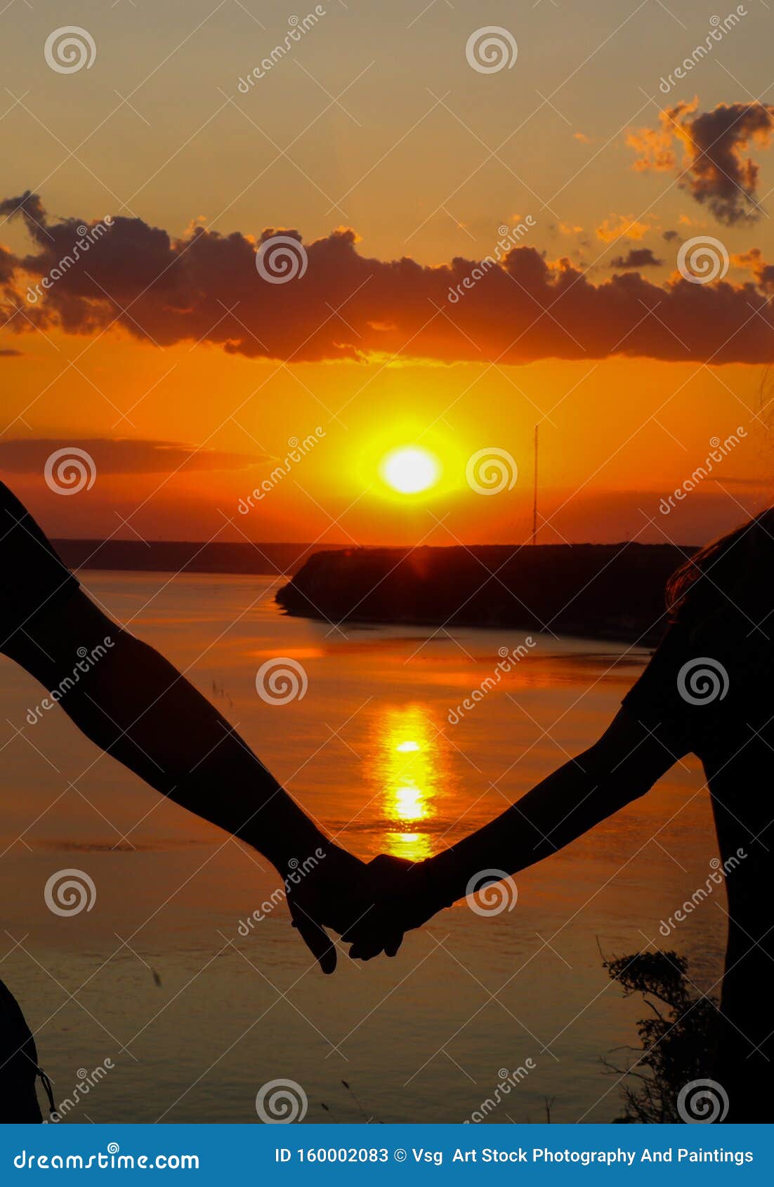 Silhouette Of Romantic Couple Holding Hands On The Beach And Looking At
