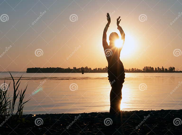 Silhouette Of Slim Woman With Hands Up In The Air Illuminated With