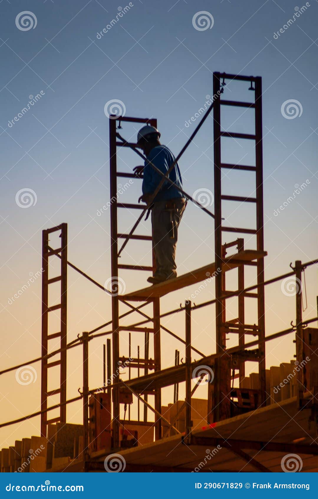 A Silhouetted Construction Worker Standing on Metal Scaffolding ...