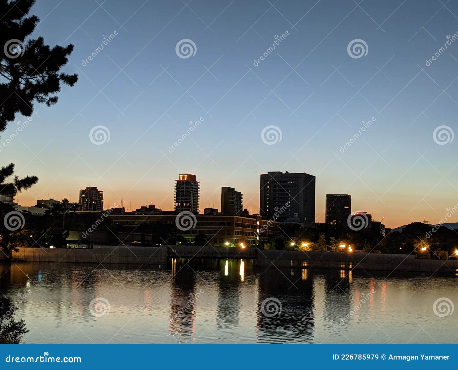 Silhouettes of Buildings in the Horizon during Sunset with Reflection ...