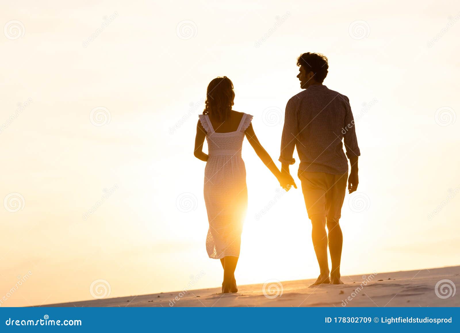 Silhouettes Of Man And Woman Holding Hands While Walking On Beach