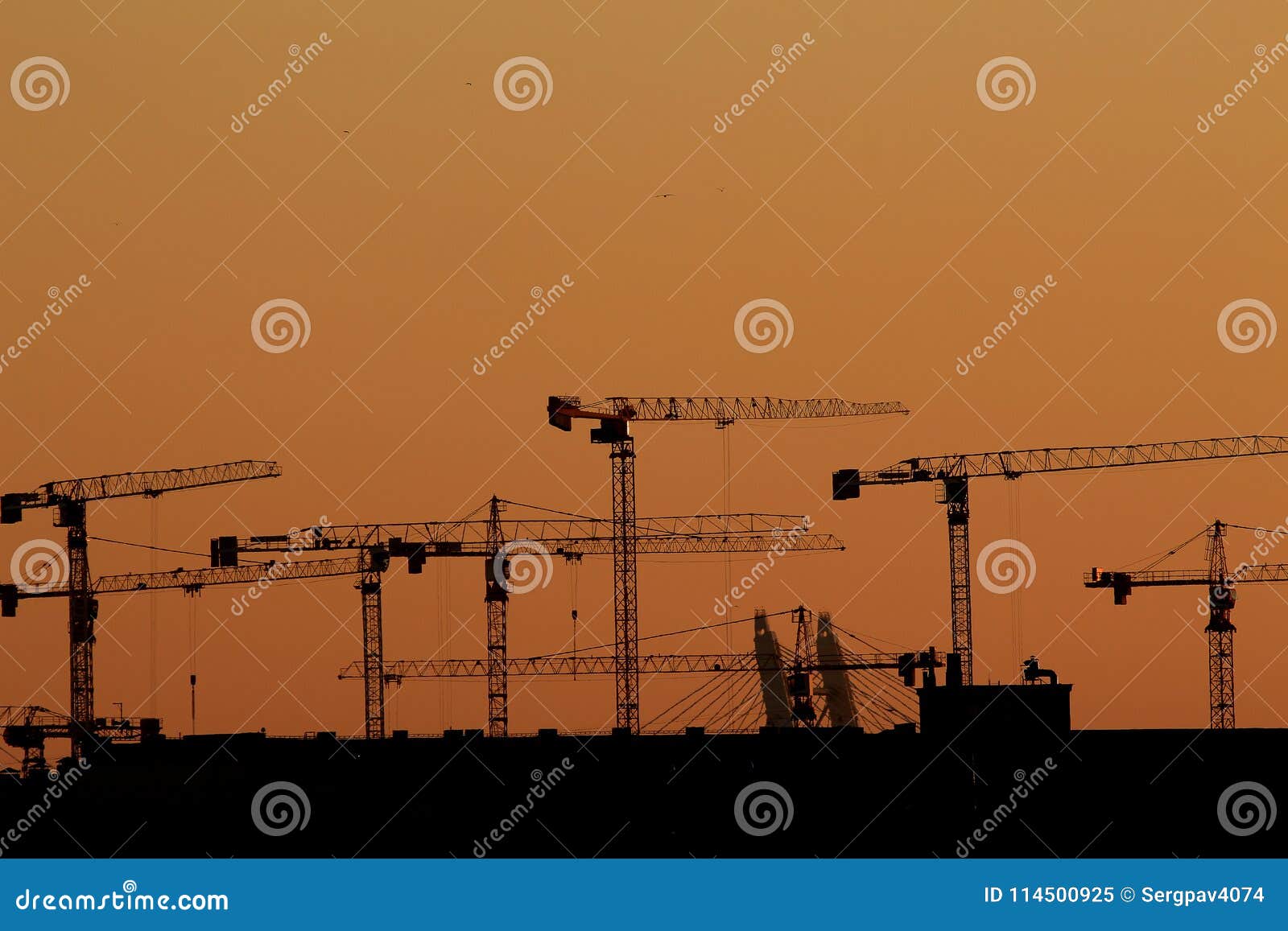Silhouettes of Tower Cranes Against the Background of the Setting Sun ...