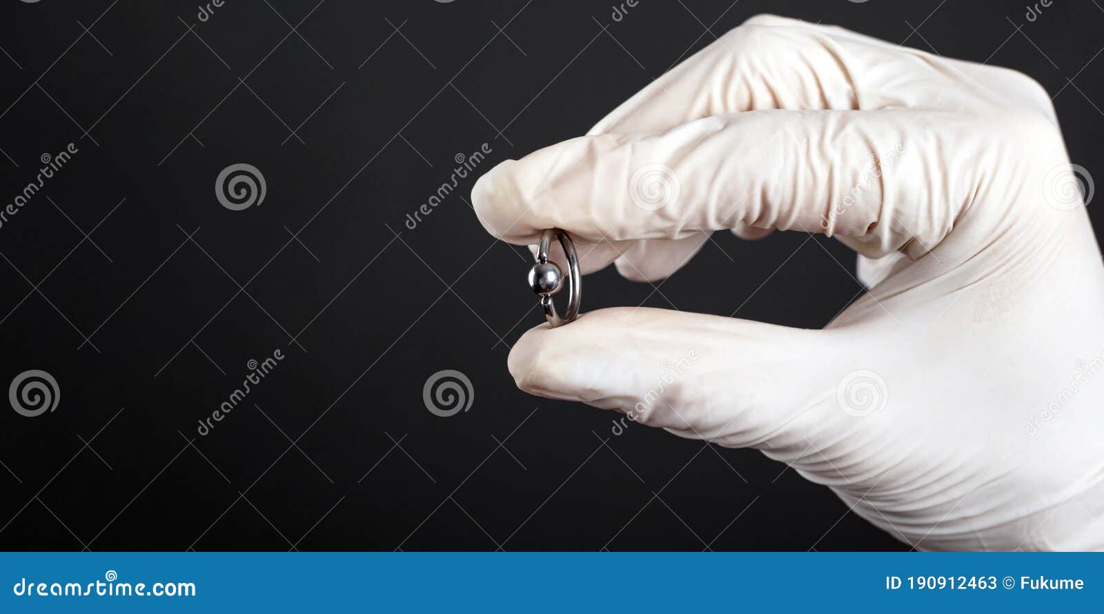 Silver Piercing Ring , Accessory for Piercing in Hand on a Dark ...