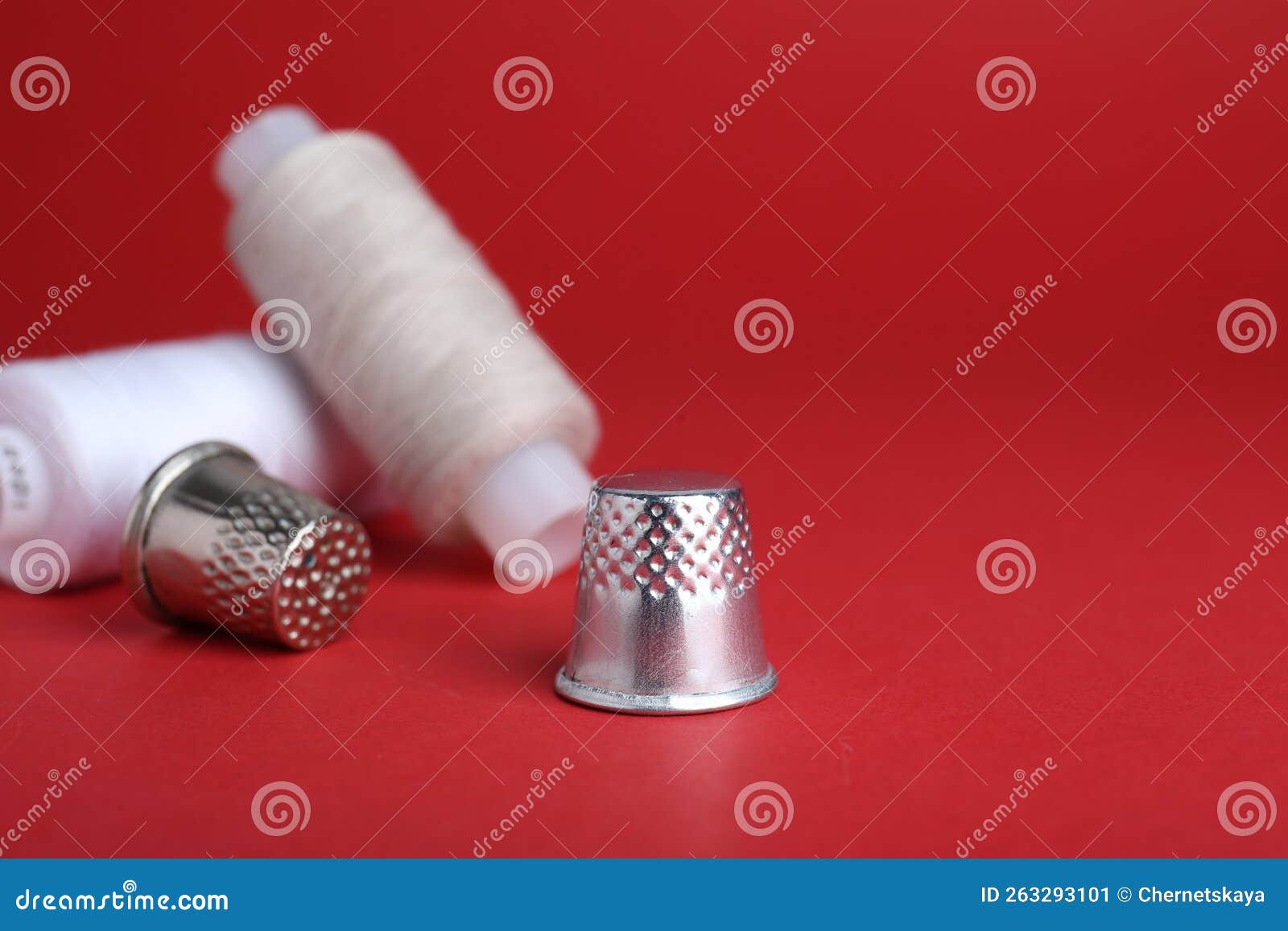 Silver Thimbles and Light Thread on Red Background. Sewing Accessories ...
