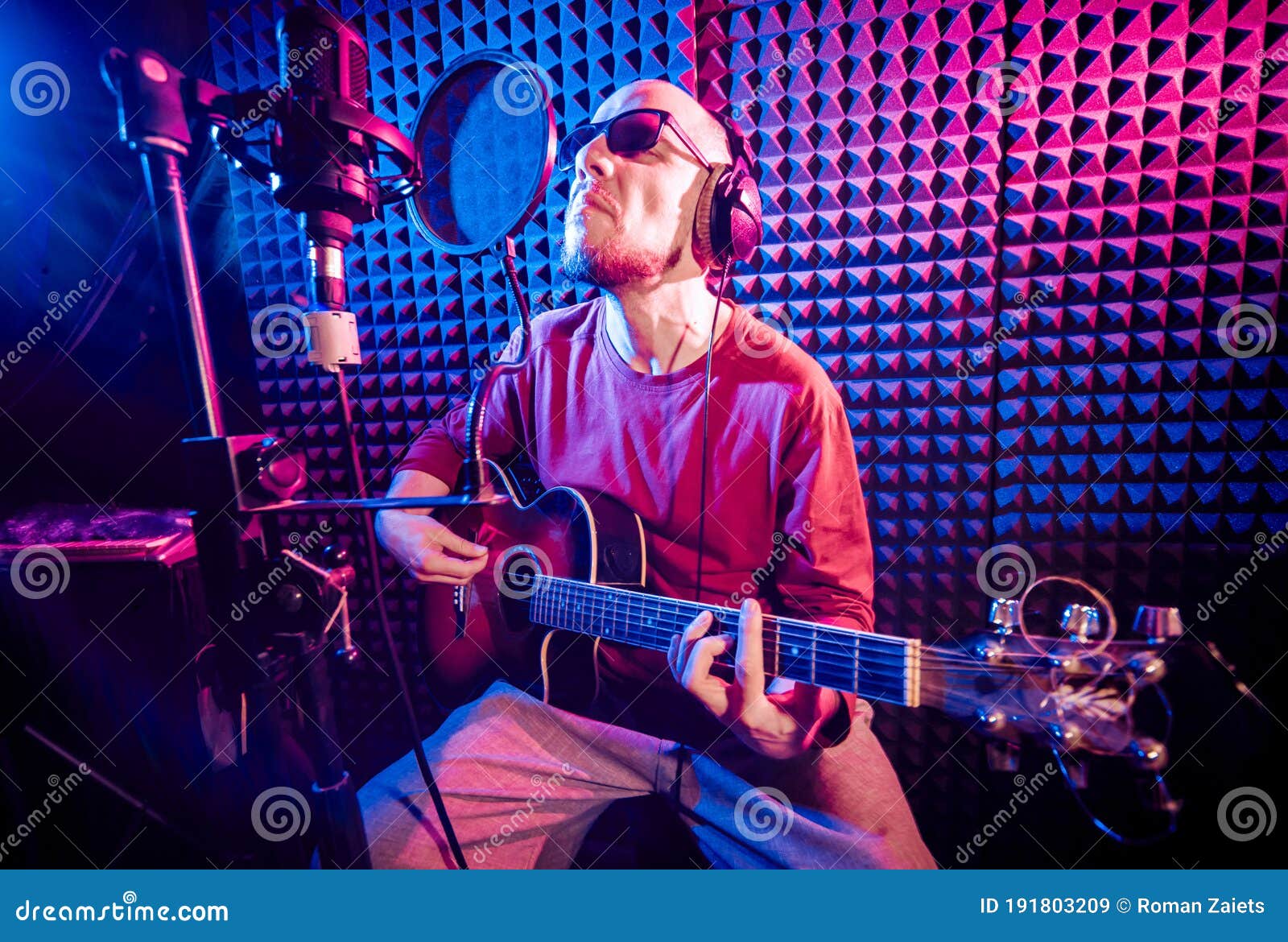 The Singer Sings with a Microphone and Playing Guitar in the Recording ...