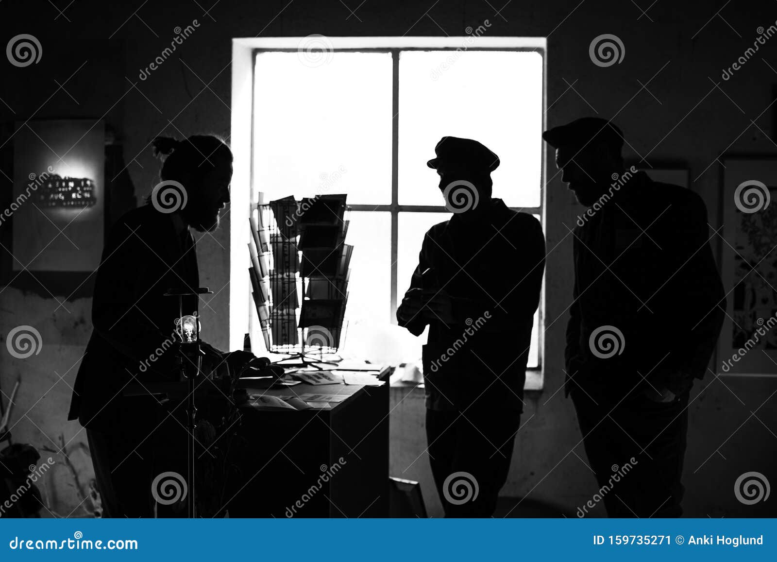 A Single Light Bulb in Focus with Silhouettes of Three Unrecognizable ...