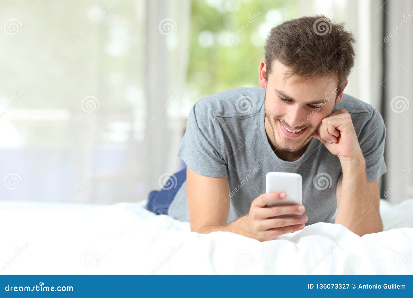 Single Man Checking Phone on a Bed Stock Image - Image of lifestyle ...