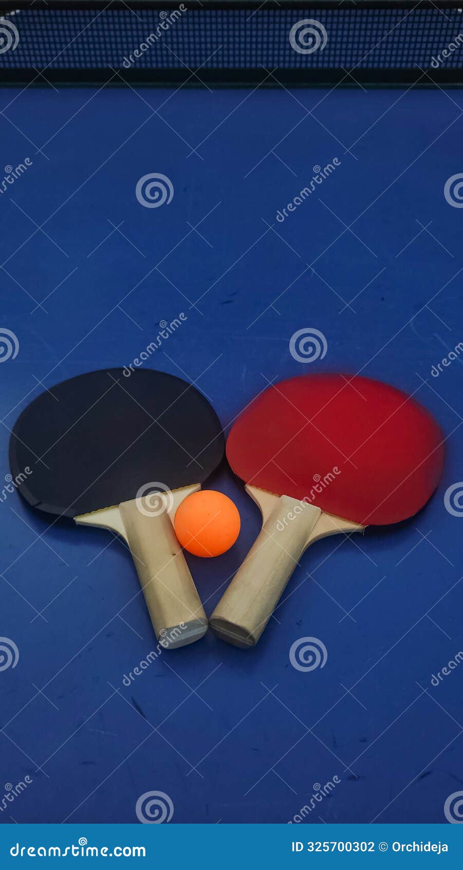A Single Orange Ping Pong Ball Sits between Two Crossed Ping Pong ...