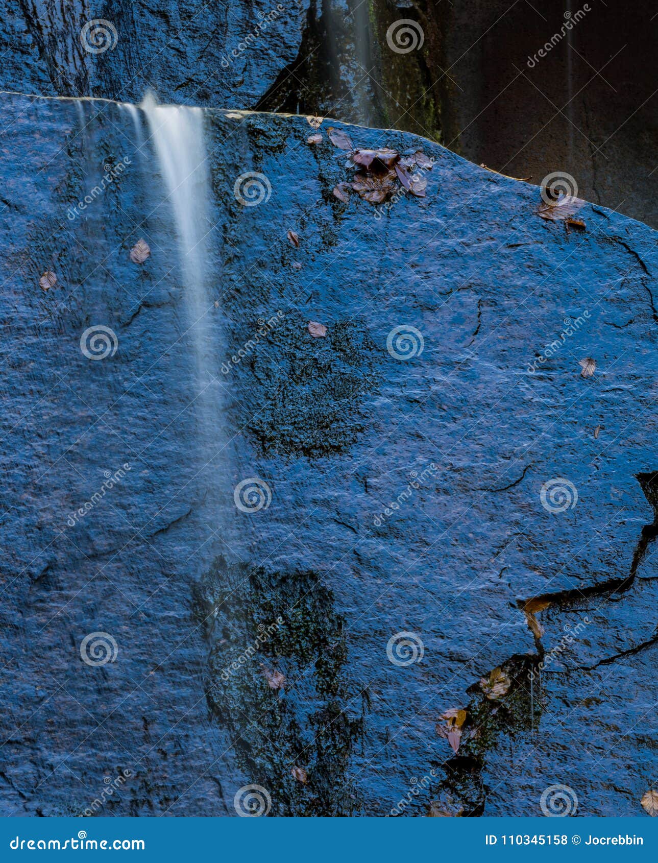 Single, Tiny Waterfall Against Shaded Blue Rock Stock Photo - Image of ...