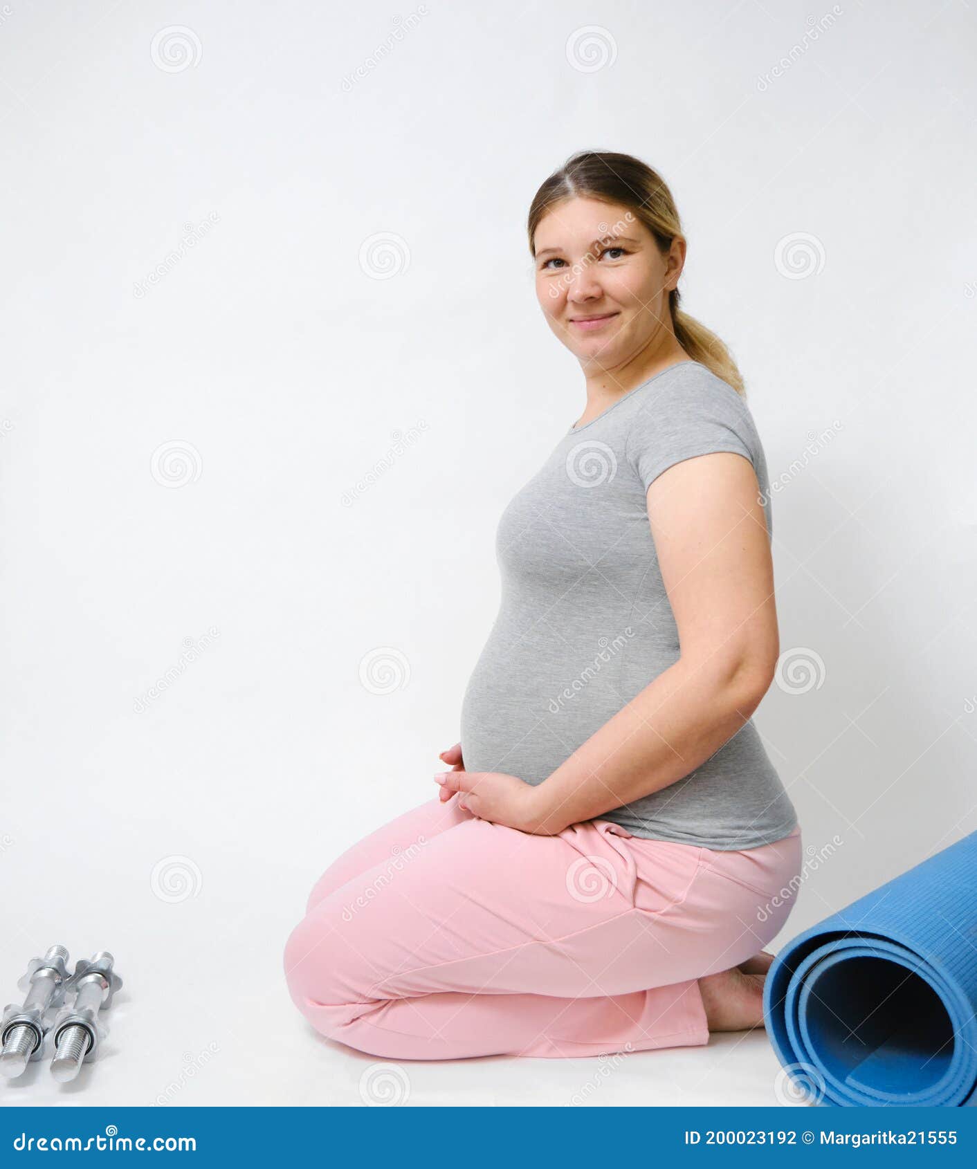 Caucasian Pregnant Woman Sitting On Her Knees On White Background Stock