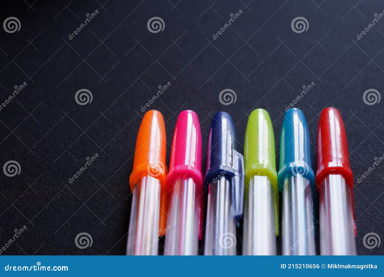 Six Multi-colored Ballpoint Pens with Protective Caps Lie on a Dark ...