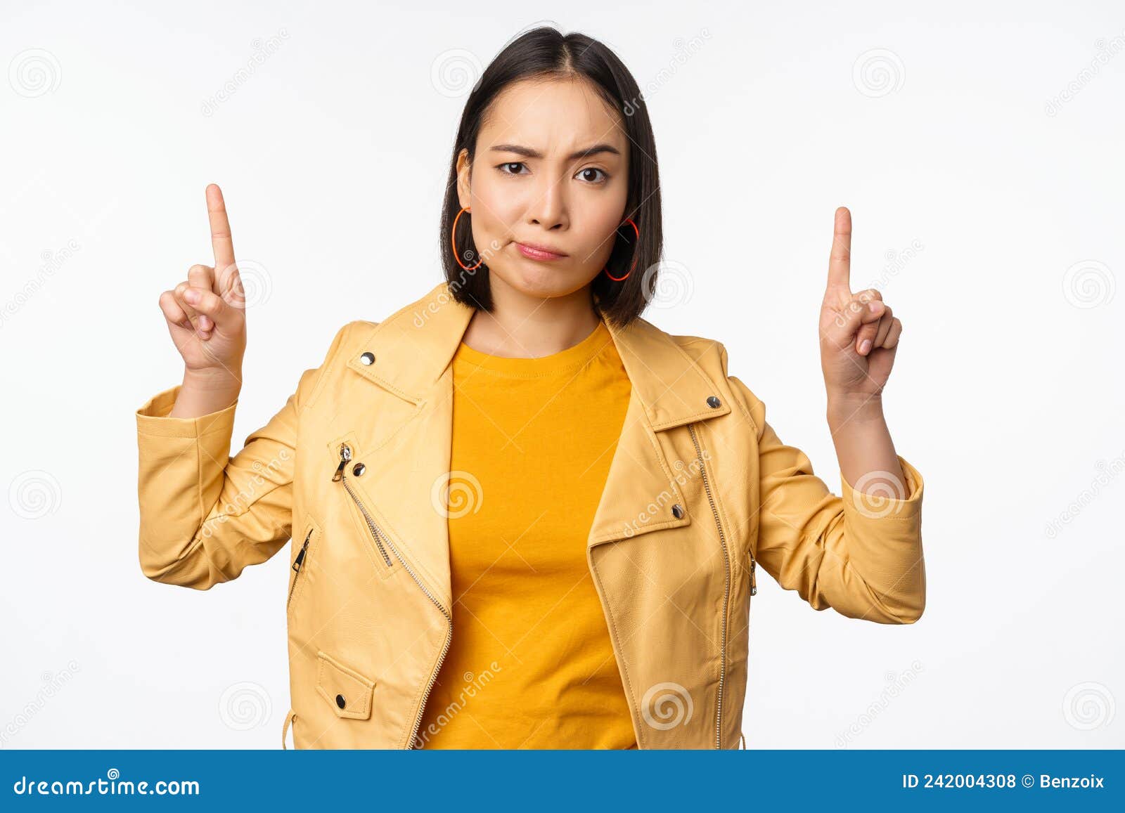 Skeptical Asian Woman Pointing Fingers Up, Frowning and Looking with ... Skeptical Asian Woman Pointing Fingers Up, Frowning and Looking with ...