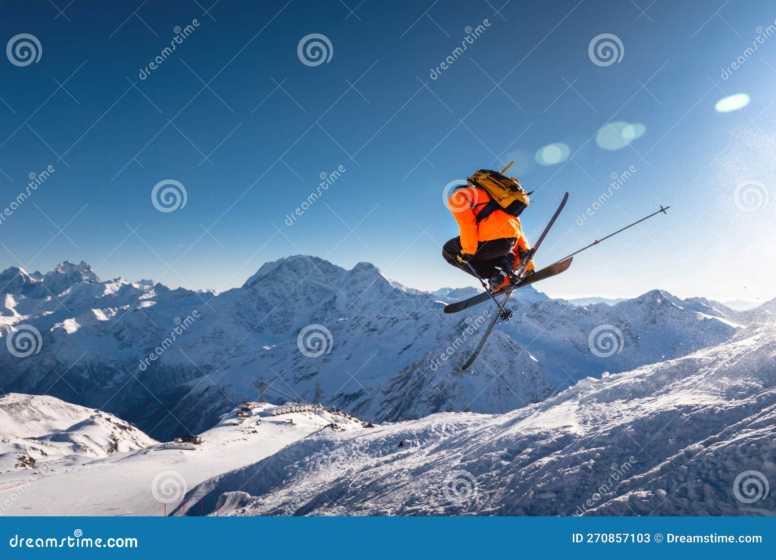 The Skier Jumps On The Background Of The Blue Sky And Snow Capped
