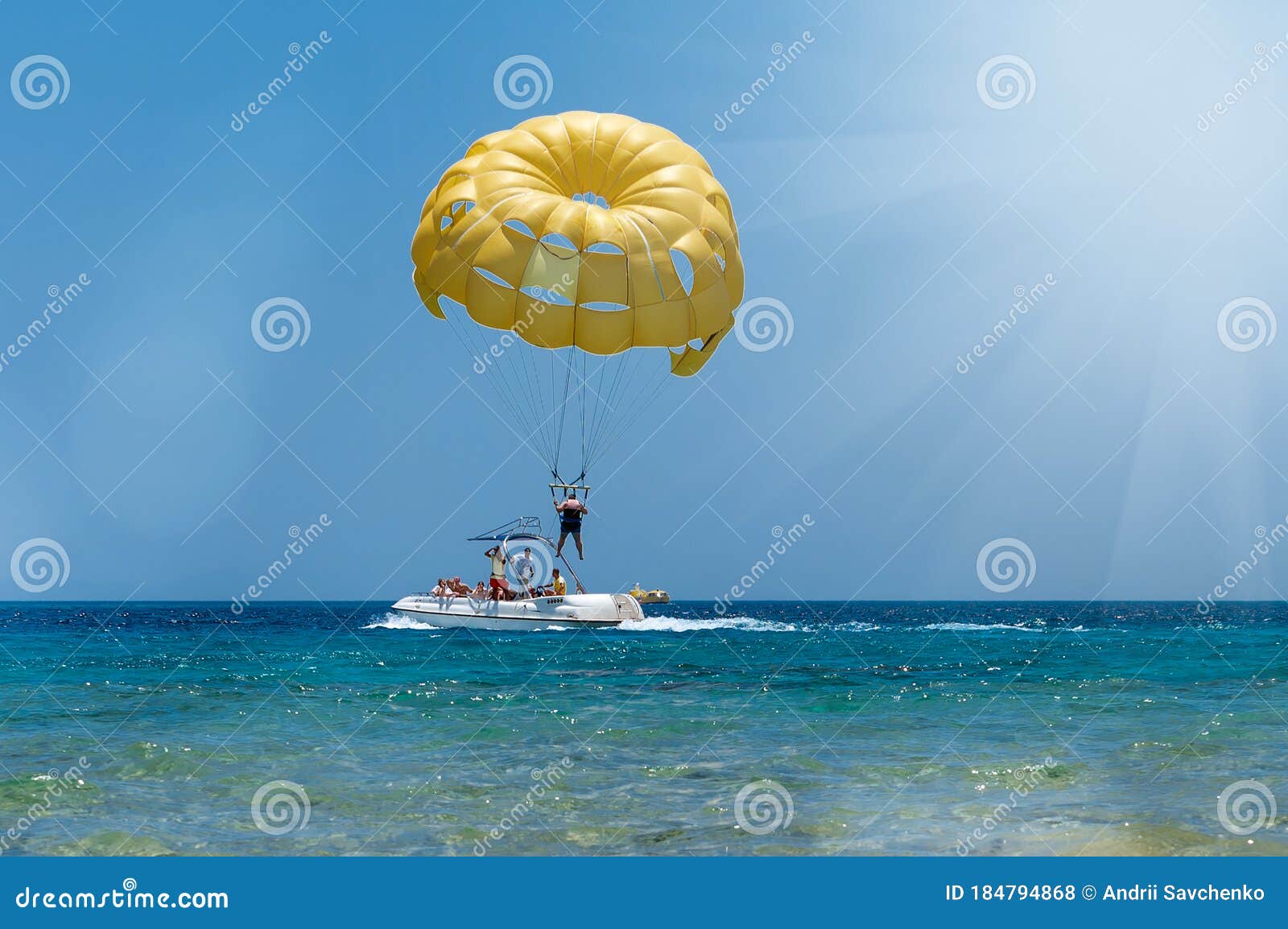 Skydiver Flying with a Yellow Parachute by Speed Boat on Sea. Skydiver ...