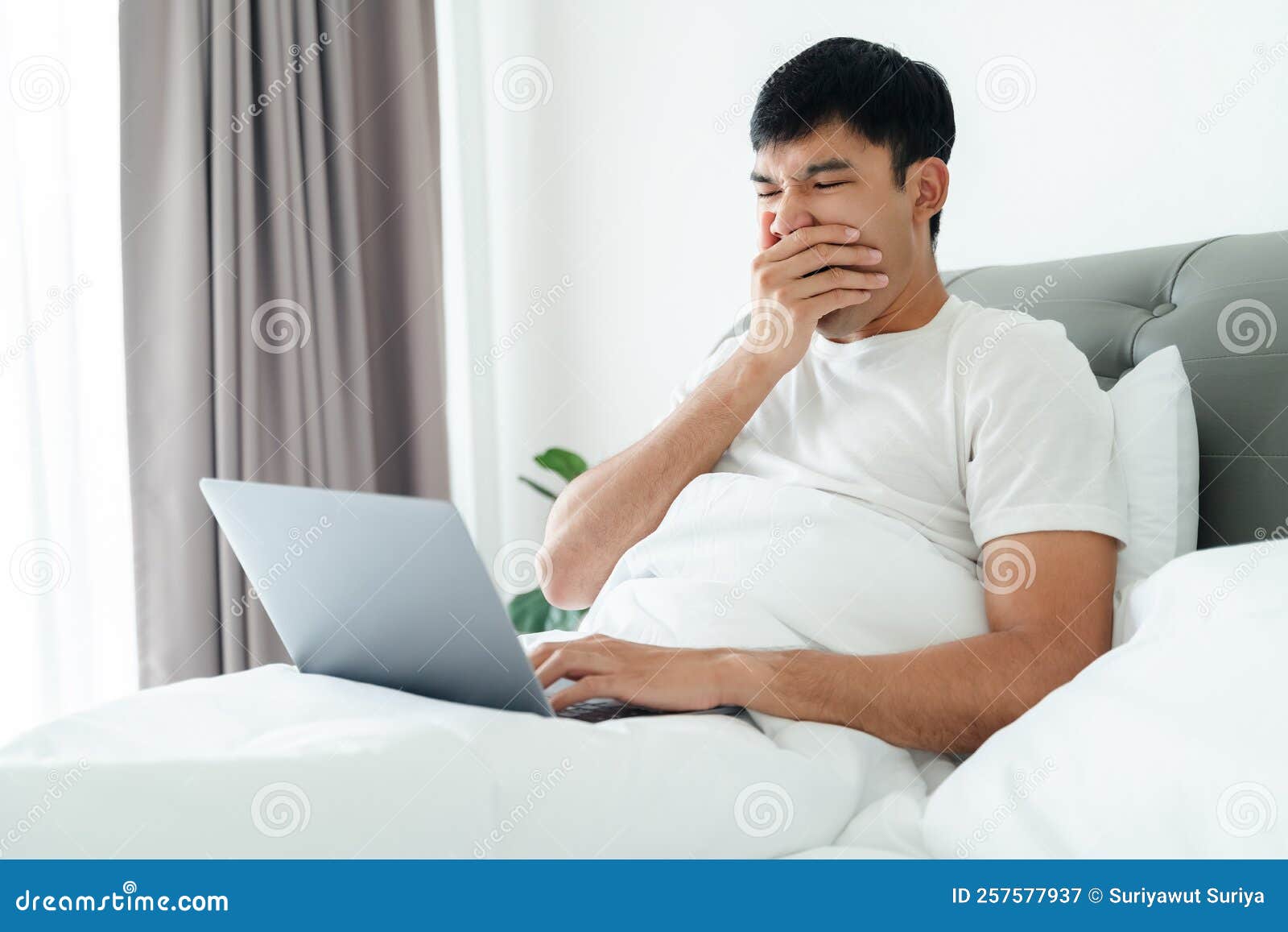 Sleepy Man Yawning on Bed Using Laptop Computer Stock Image - Image of ...