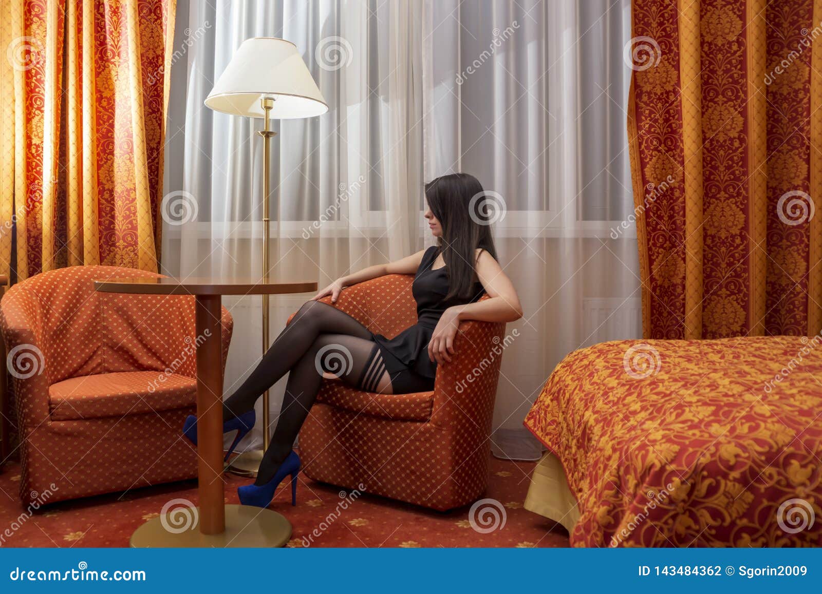 Slender Girl In High Heels Short Dress And Black Stockings In Chair In