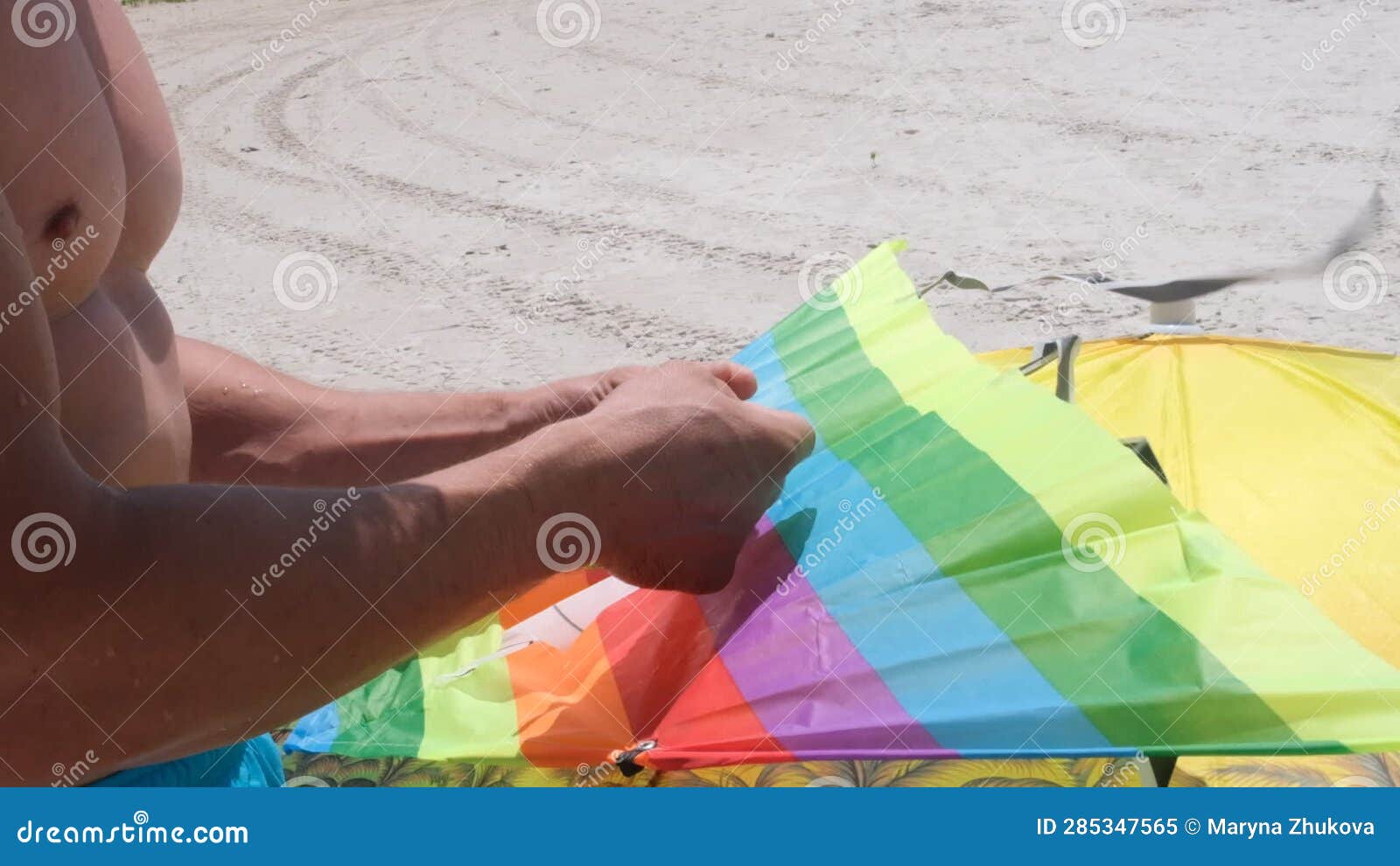 A Slender Man on the Beach is Flying a Multi-colored Kite. Active ...