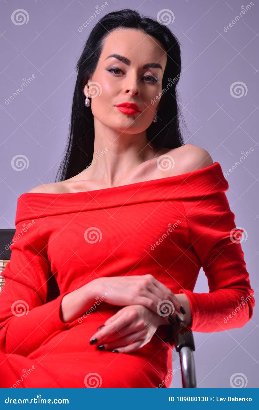 Slender Model in an Elegant Red Dress and Knee-high Heels Posing in the ...