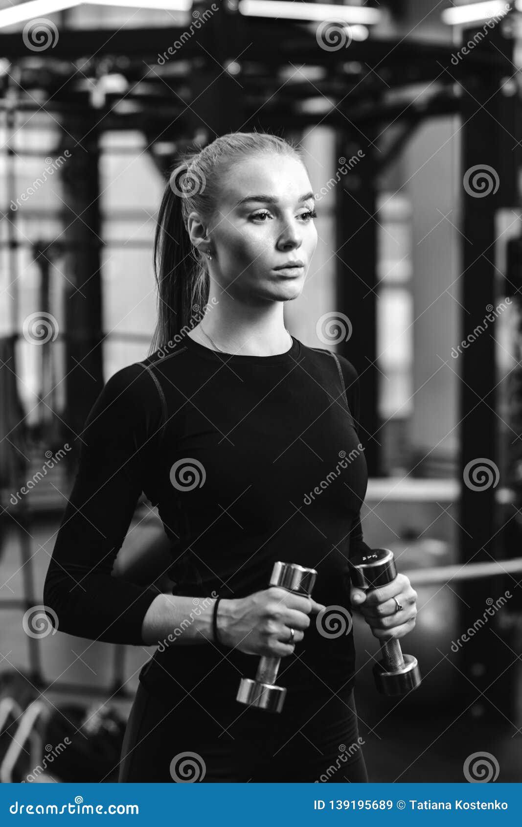 Slender Young Girl Dressed In A Black Sportswear Is Doing Exercises