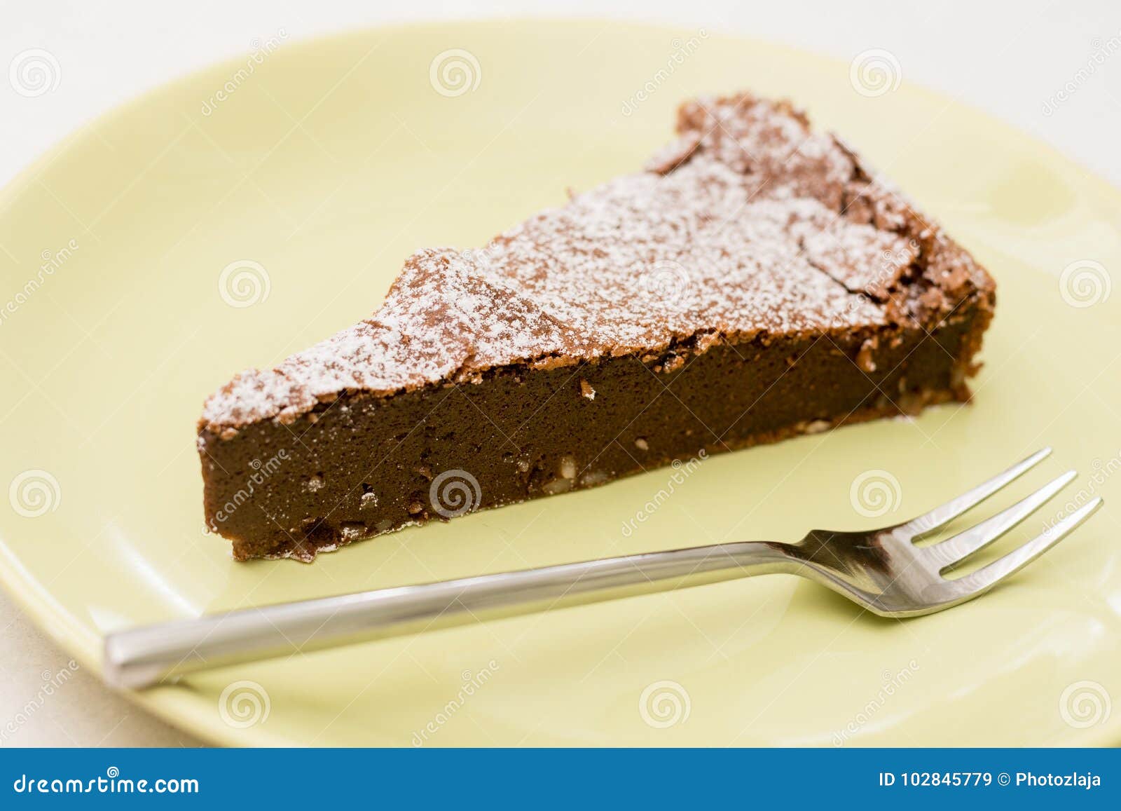 Slice of Chocolate Cake with Powdered Sugar and Metal Fork on the Green ...