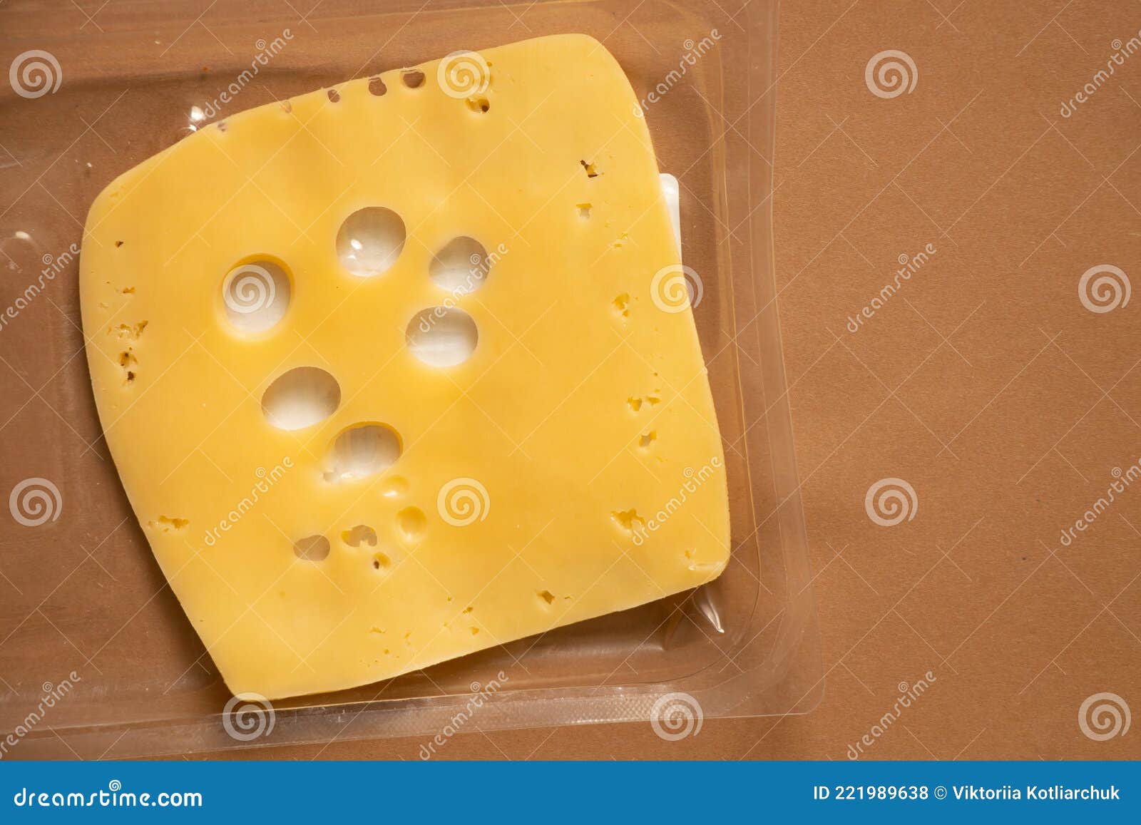 Slice of Hard Yellow Cheese in Plastic Wrapping on Brown Paper Stock ...