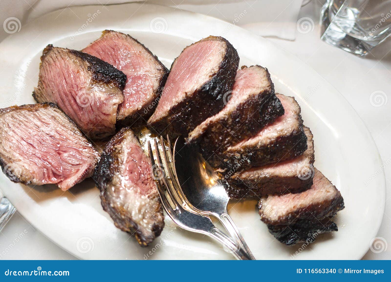 Seared Medium Rare Stake Cut on White Plate with Spoon and Fork Stock ...