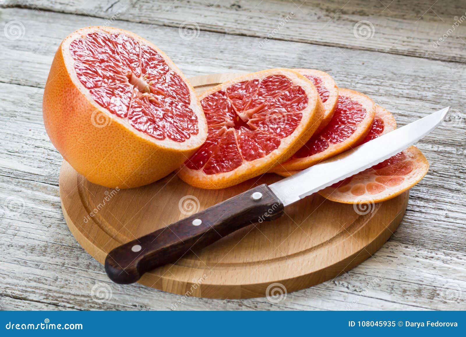 Sliced Pieces of Grapefruit with a Knife. on White Wooden Background ...