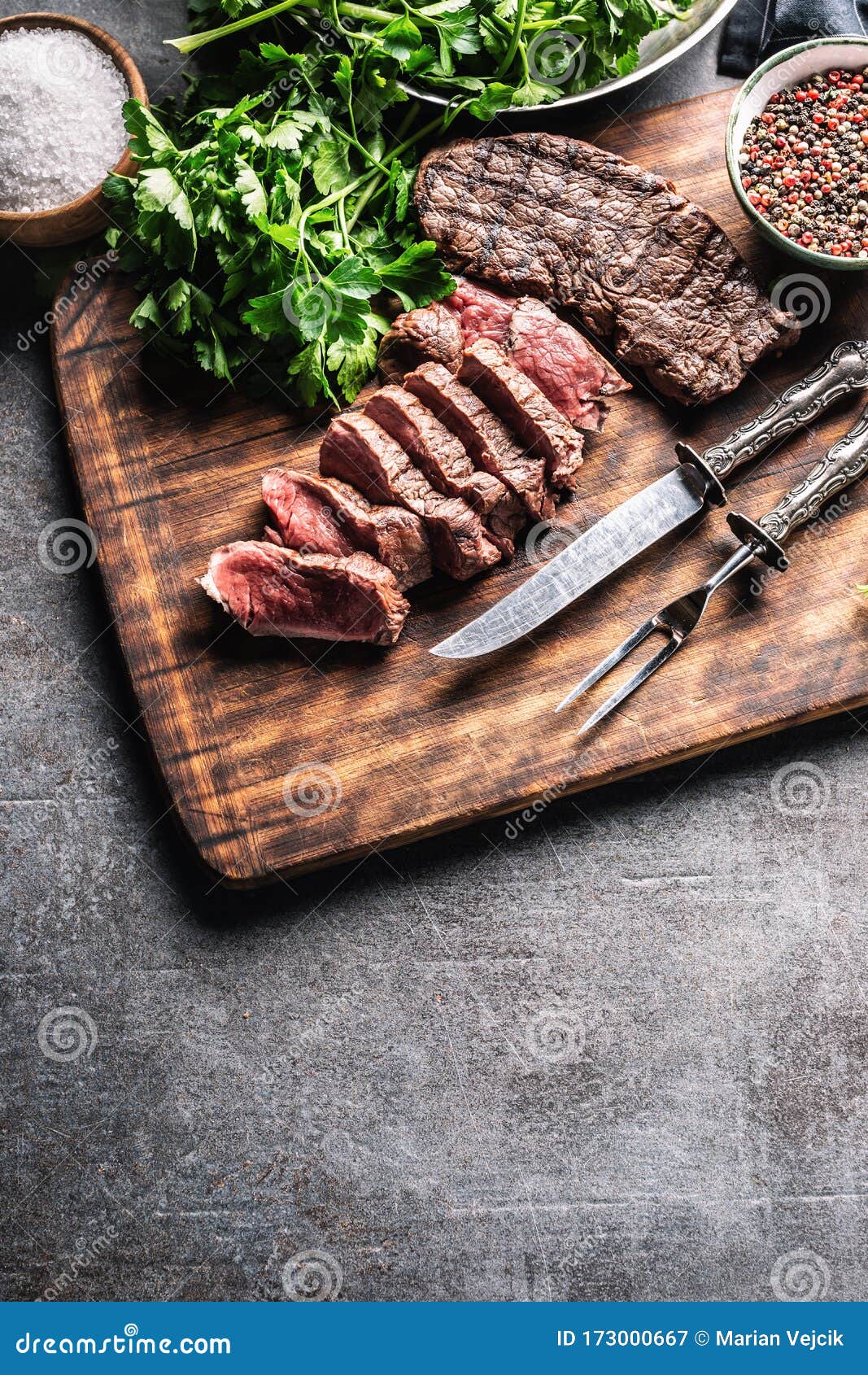 Slices of Juicy Grilled Beef Steak with Fork and Knife on a Butcher ... Slices of Juicy Grilled Beef Steak with Fork and Knife on a Butcher ...