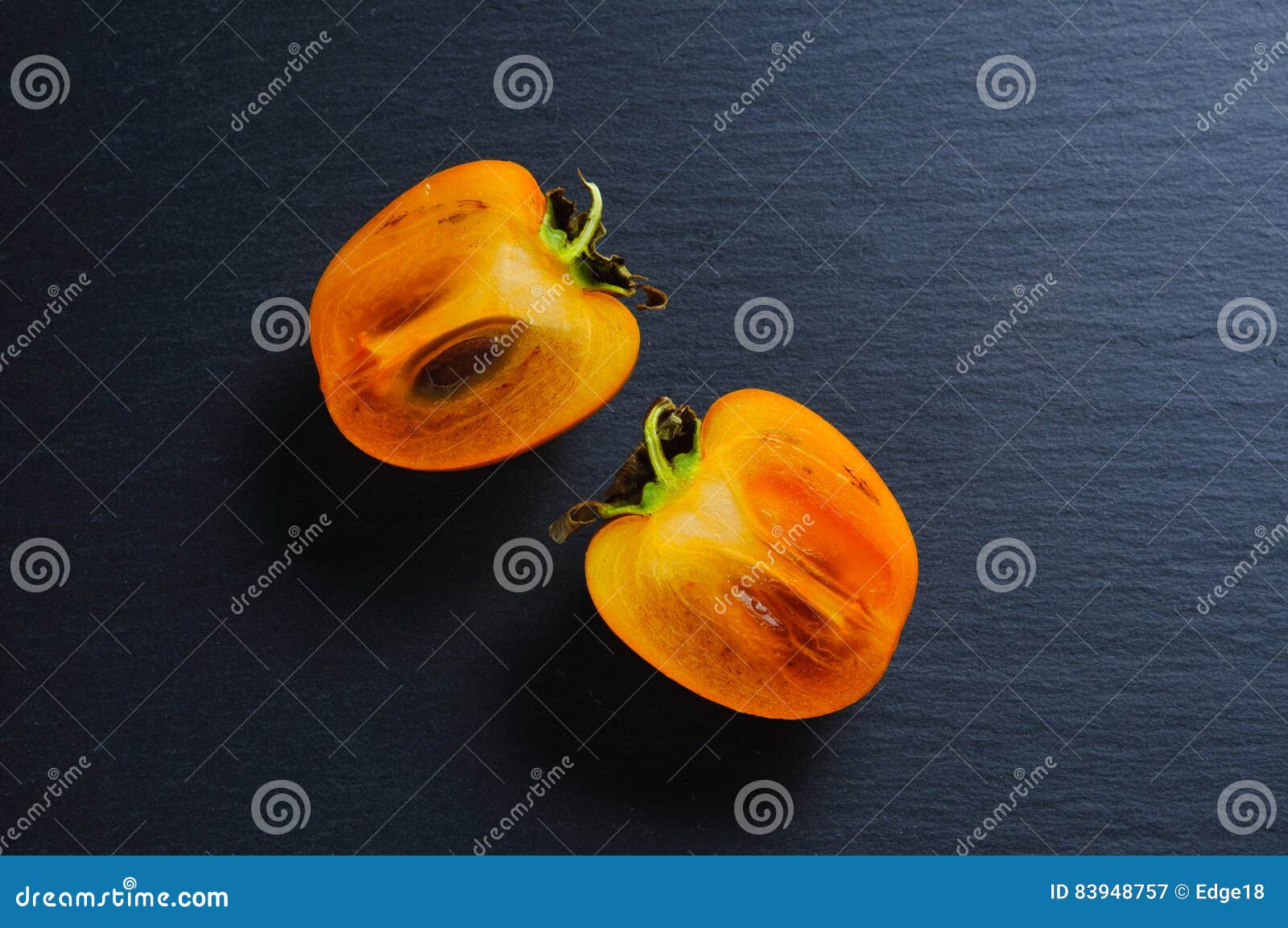 Slices of Persimmon on Black Slate Stone Background. Top View Stock ...