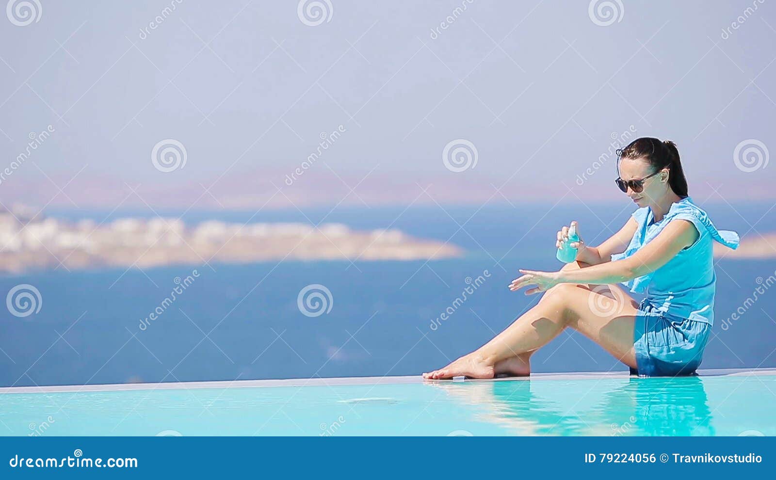 Slim Woman Applying Sunscreen On Her Legs Sitting On The Edge Of Pool