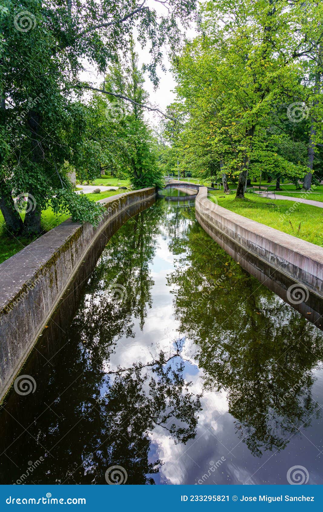 Small Bridge Over Quiet Water Channel in the Park Next To Large Trees ...