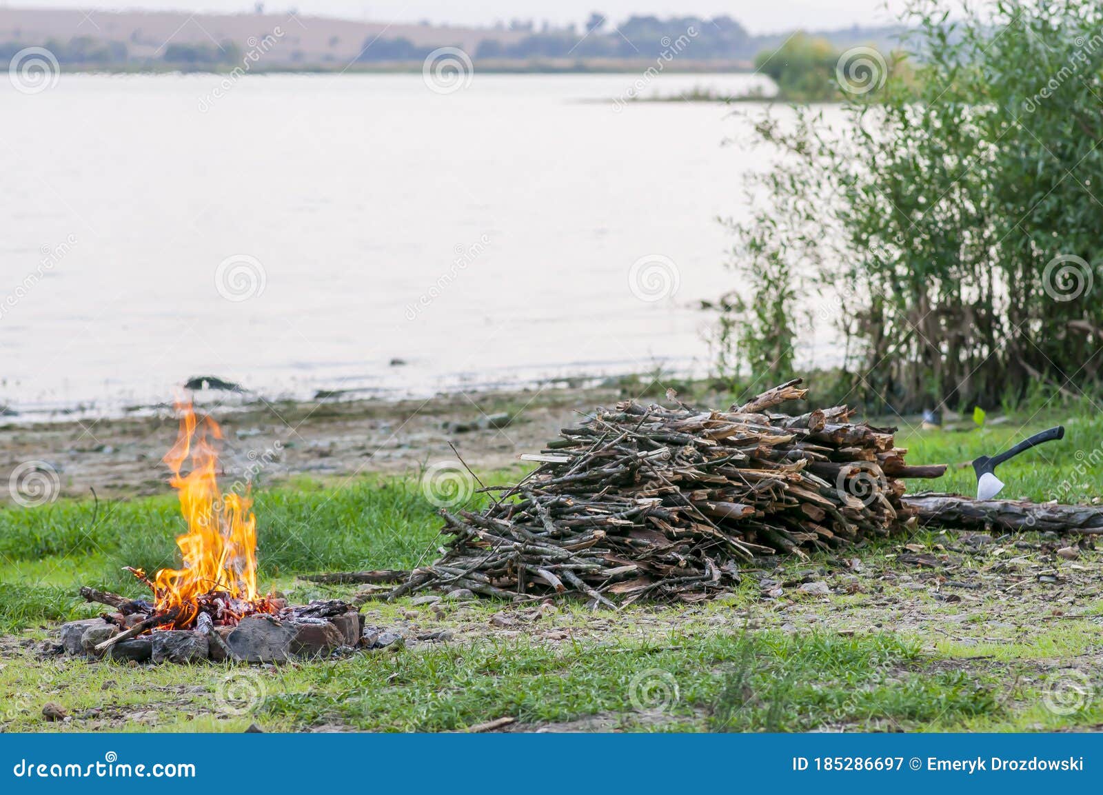Small Campfire with Flames beside a Lake with Wood Pile on the Side ...