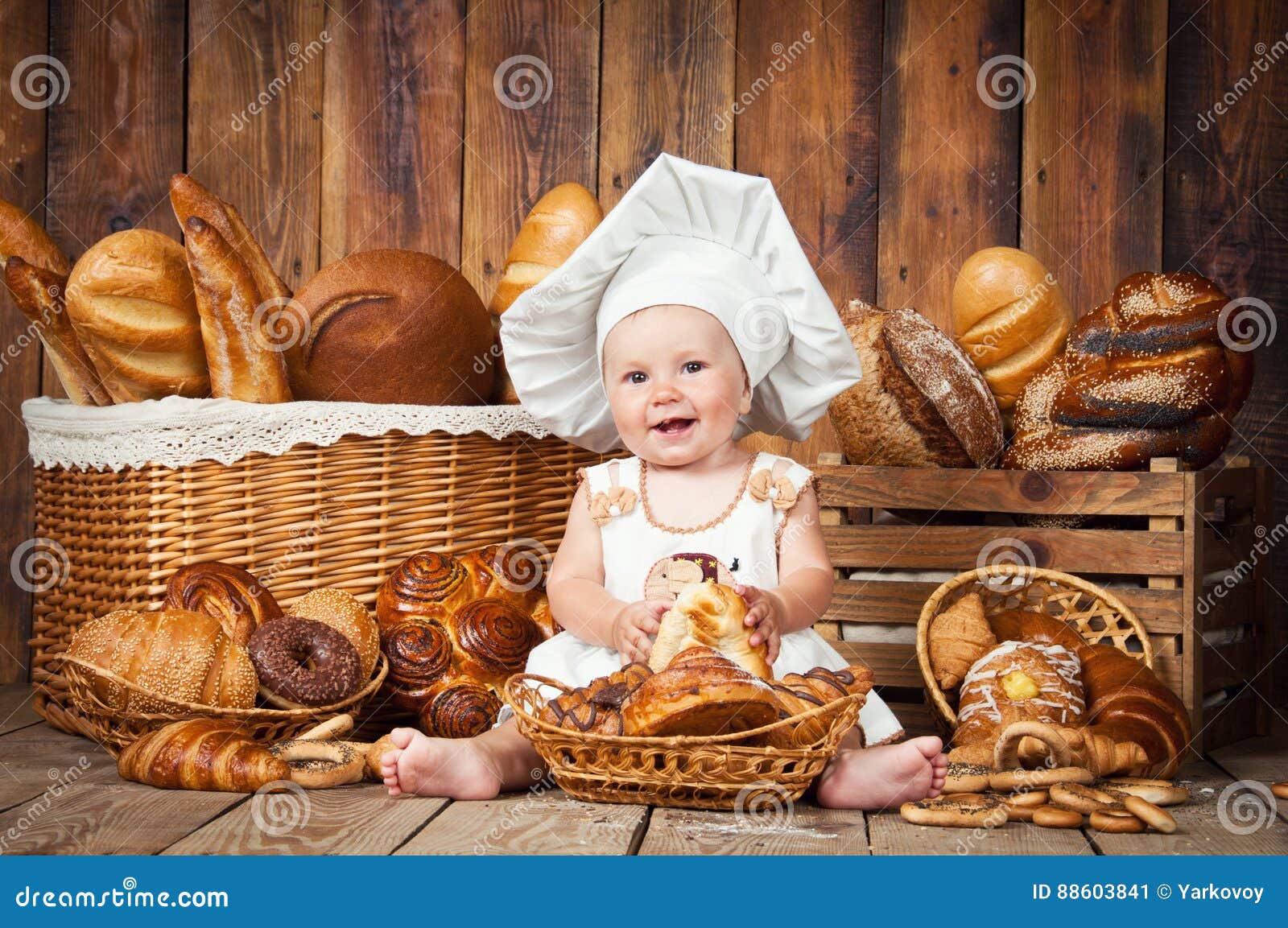 Small Child Cooks A Croissant In The Background Of Baskets With Rolls ...