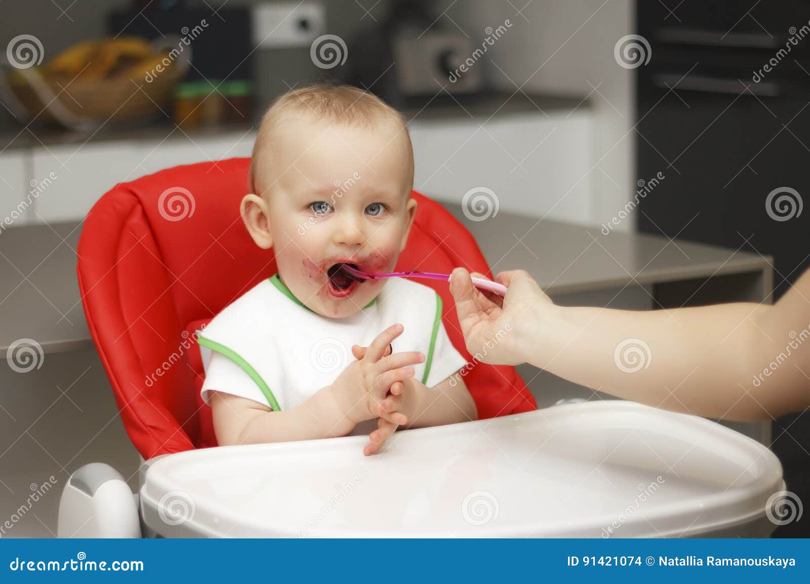 A Small Child Eats Jam and Cereal, Sits on a Highchair Stock Photo ...