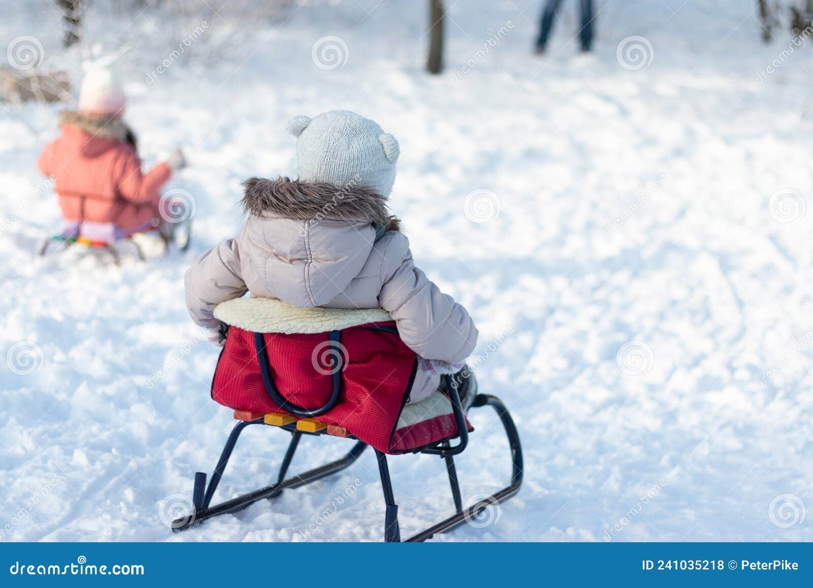 A Small Child in Warm Clothes and a Hat Slides Down a Hill on a Sled ...