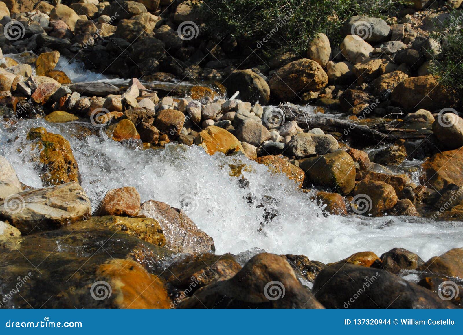 A rushing creek over rocks stock photo. Image of colors - 137320944