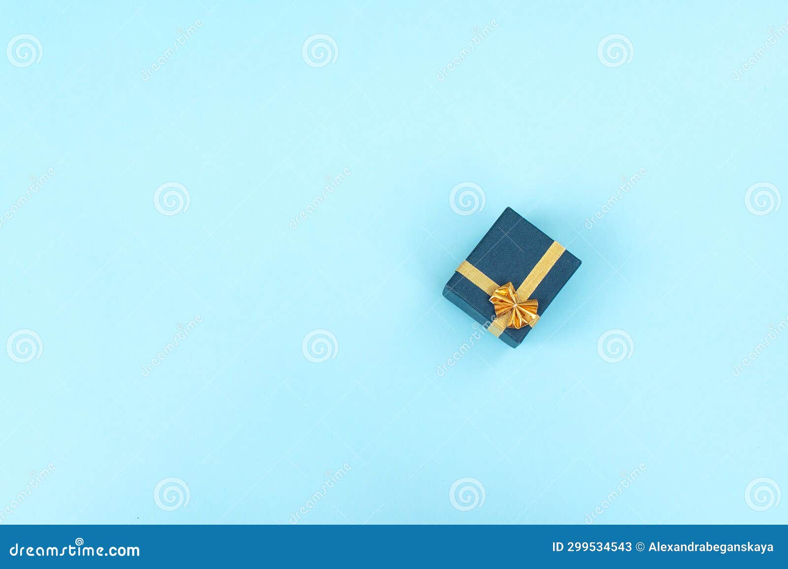 A Small Gift Box with a Gold Ribbon and a Bow on a Blue Background ...