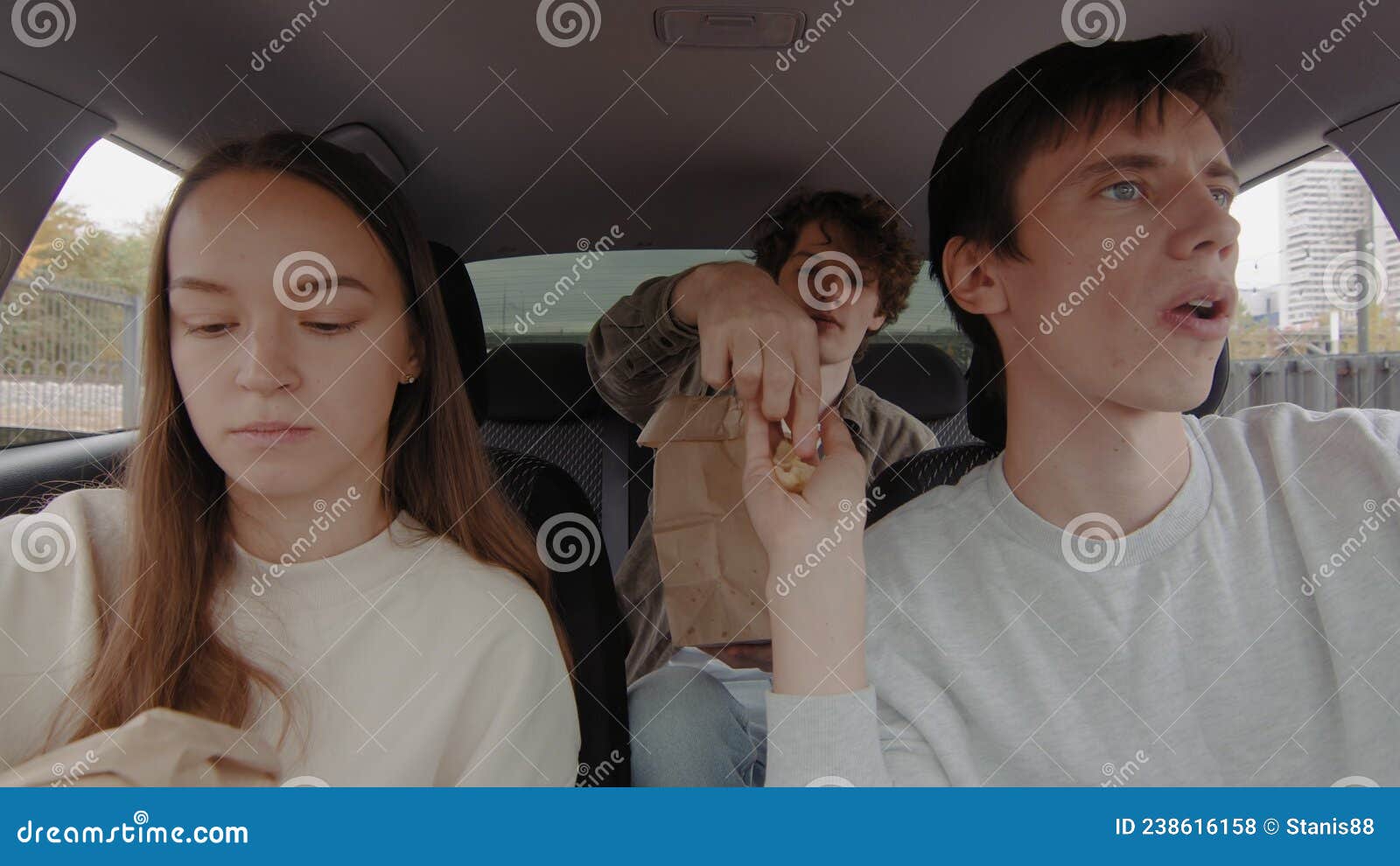 A Small Group of People are Driving in a Car and Eating Potato Chips ...