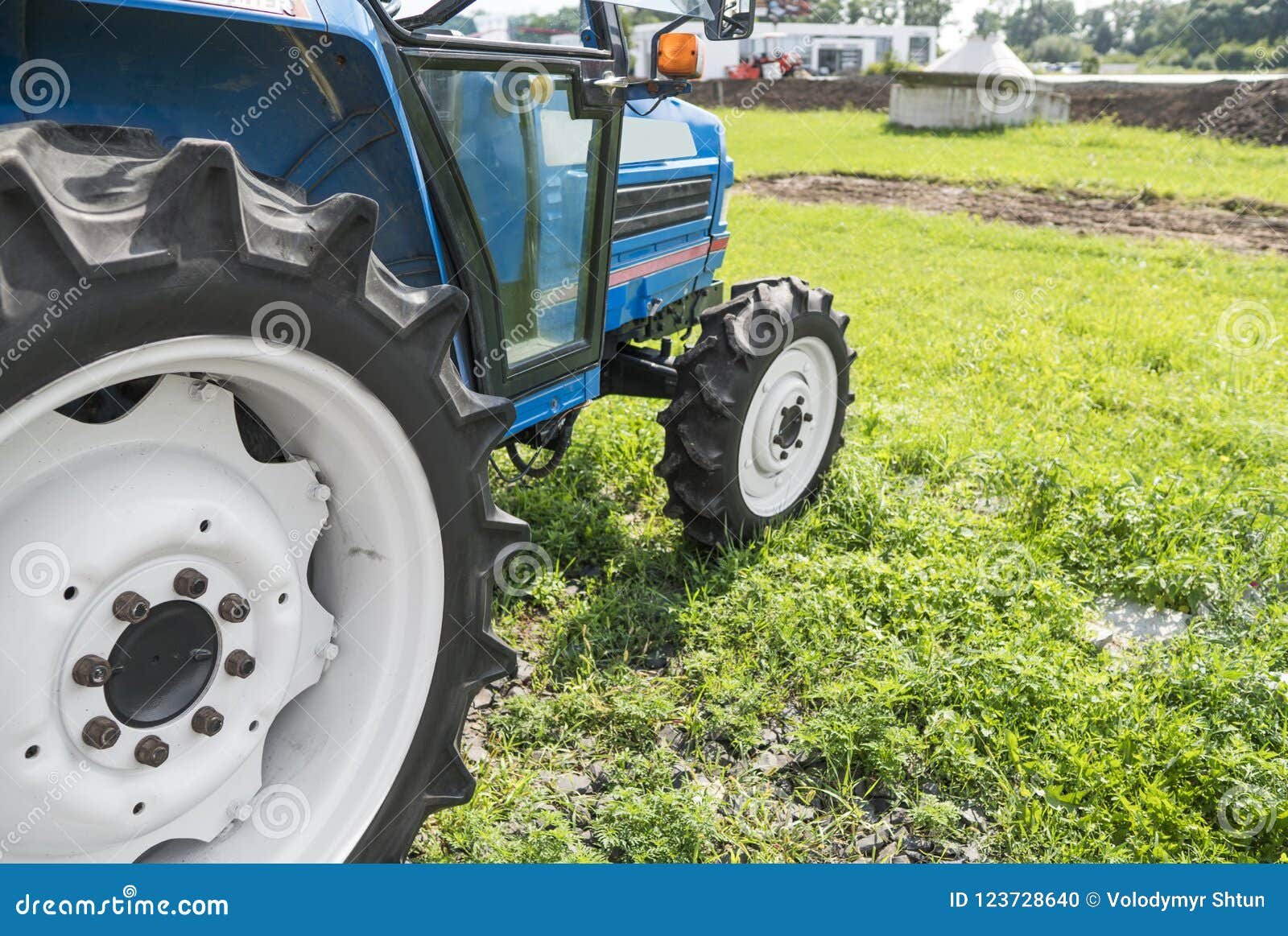A Small Mini Blue Tractor Stands on a Farm Yard on Green Grass and ...