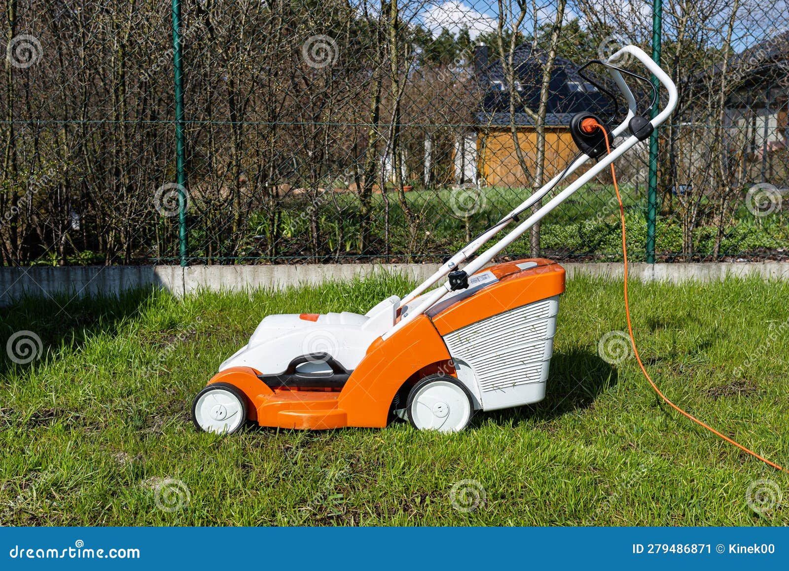 A Small Motorized Electric Mower Standing on the Lawn, it is Orange in ...