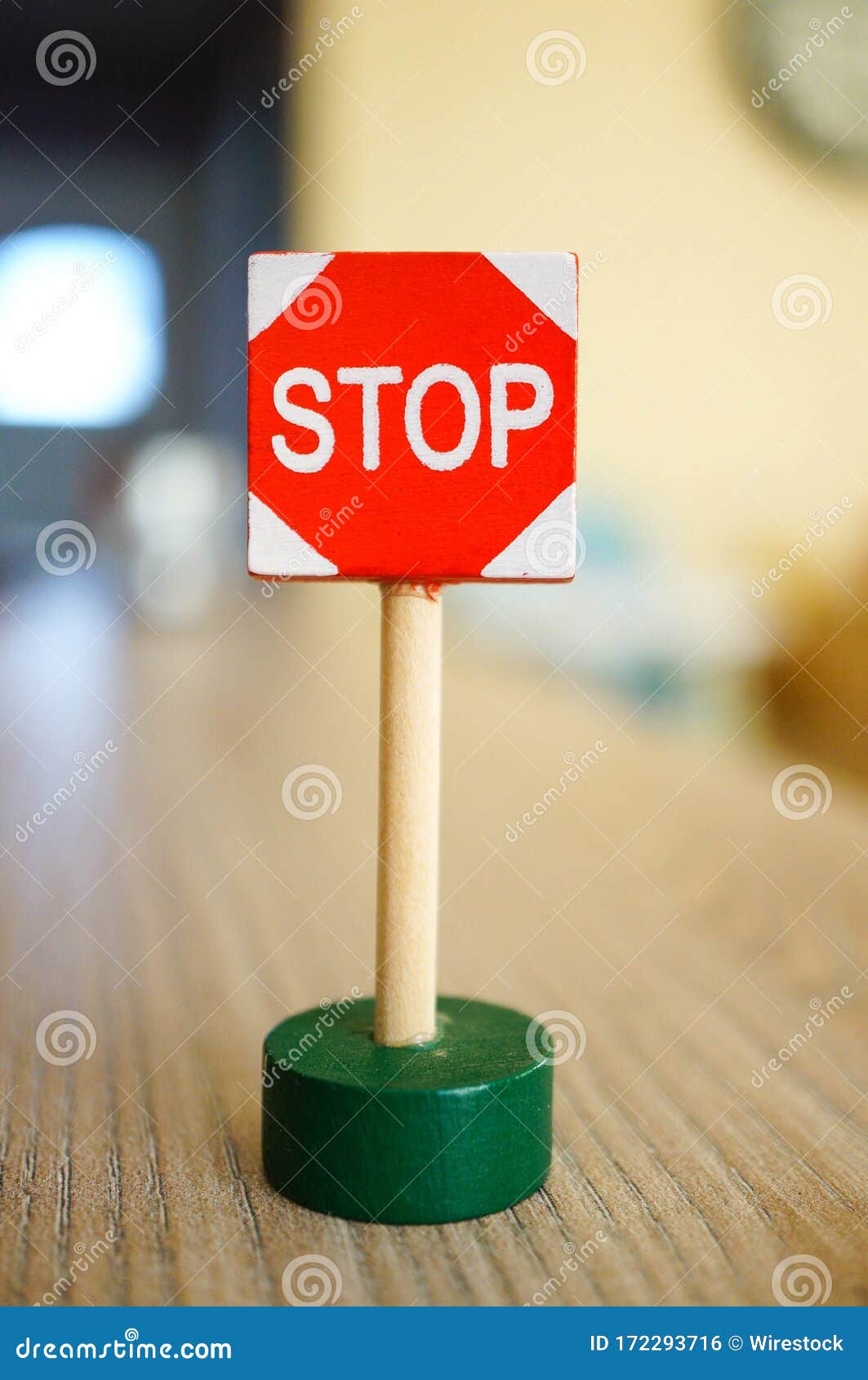 Small Red Stop Sign on a Wooden Table Under the Lights with a Blurry ...