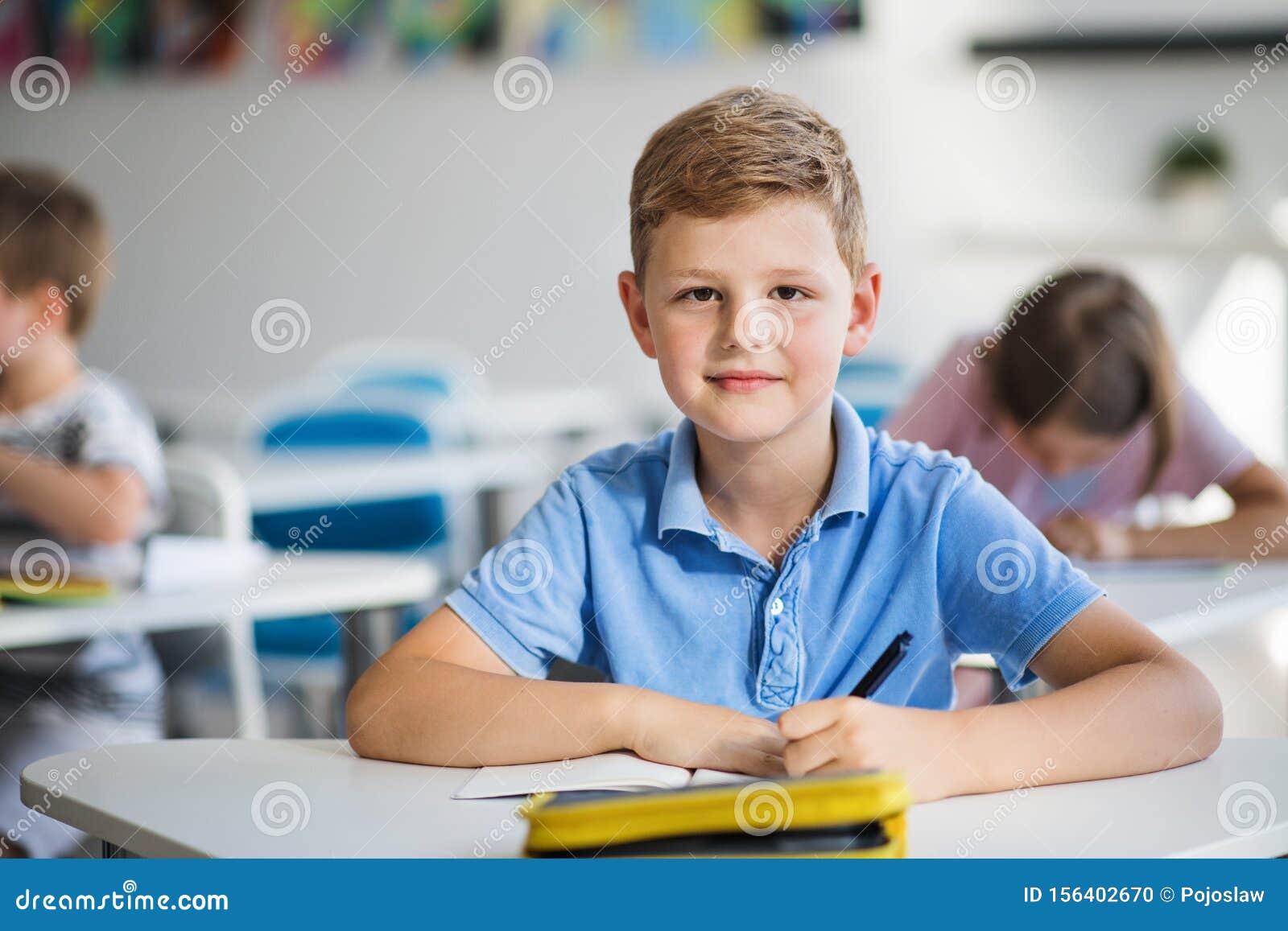 A Small School Boy Sitting at the Desk in Classroom on the Lesson ...