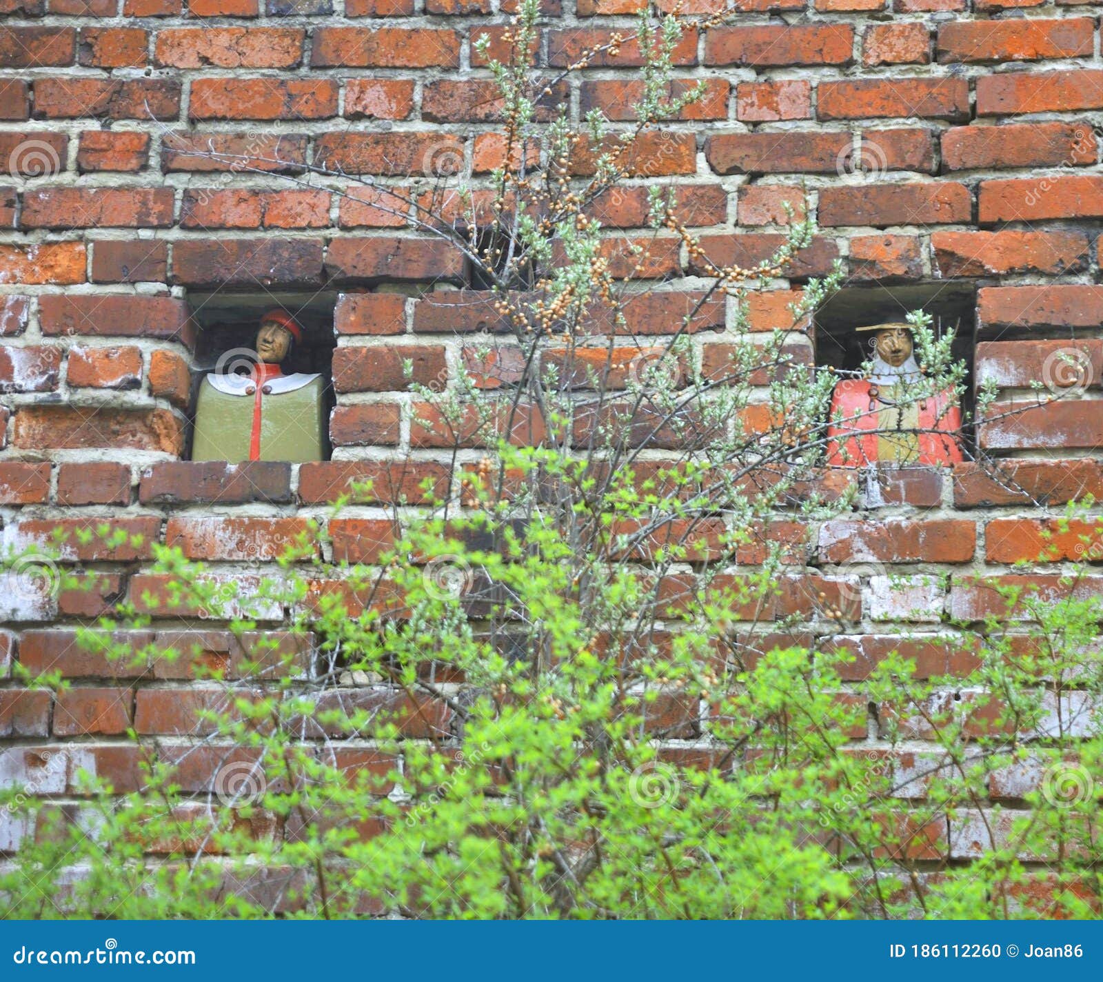 Small Sculptures of Two People Looking from Windows in Brick Wall of ...