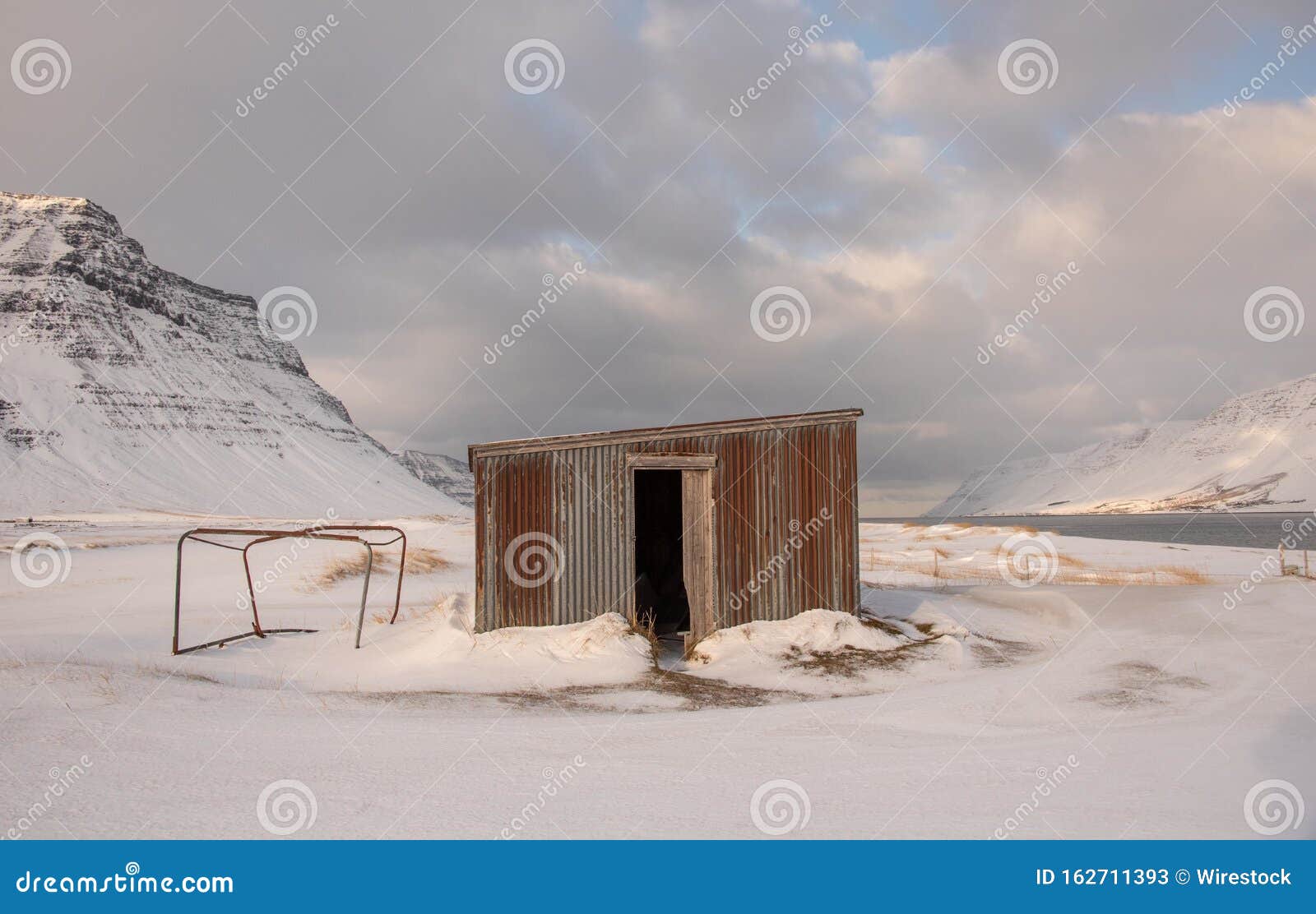 Small Shack House Surrounded by Snowy Mountains Under a Cloudy Sky ...