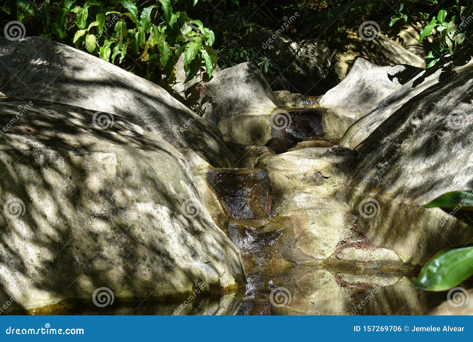 Shallow Waterfall Basin With Overhanging Cliff Edge In A Green Forest ...
