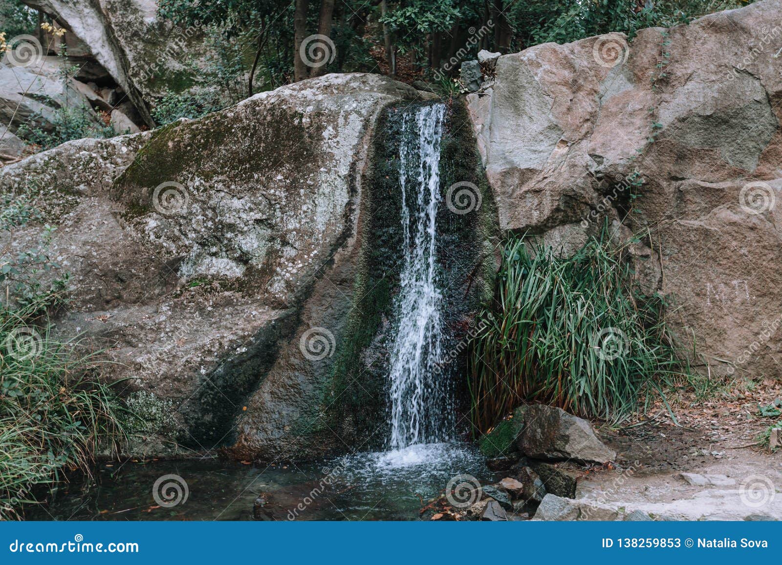 A Small Waterfall Immersed in the Spring Green Trees. Stock Image ...